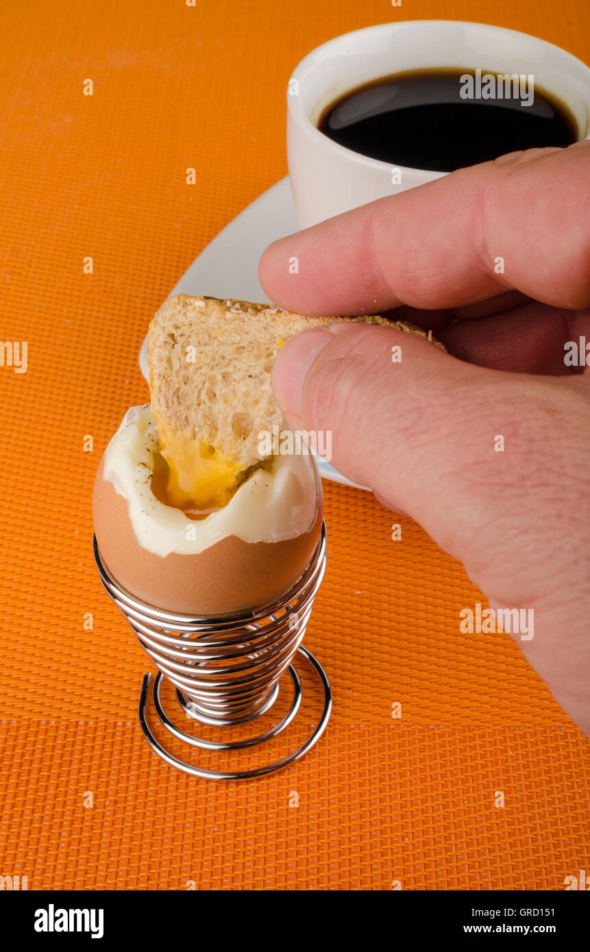 Male hand dunking a piece of toast into egg yolk Stock Photo - Alamy