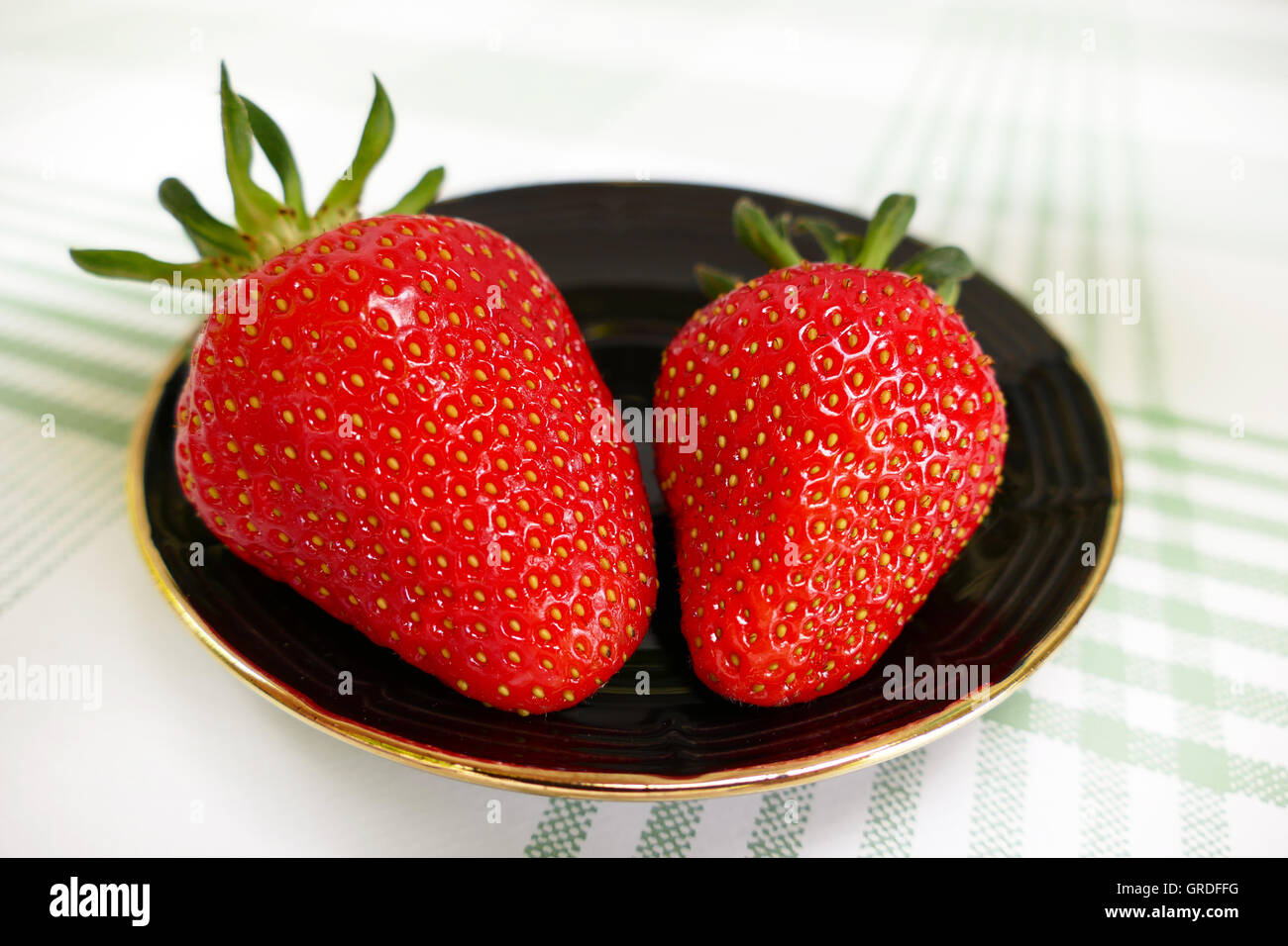 Two Strawberries On A Black Plate Stock Photo - Alamy