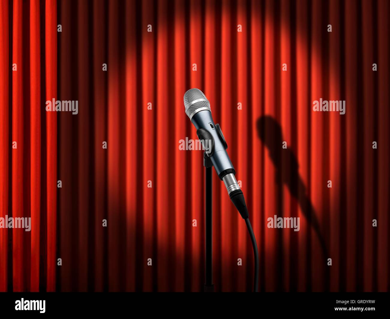 Microphone under spotlight over red curtains Stock Photo - Alamy