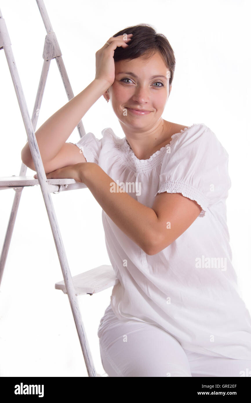 Smiling woman sitting on step ladder Stock Photo - Alamy