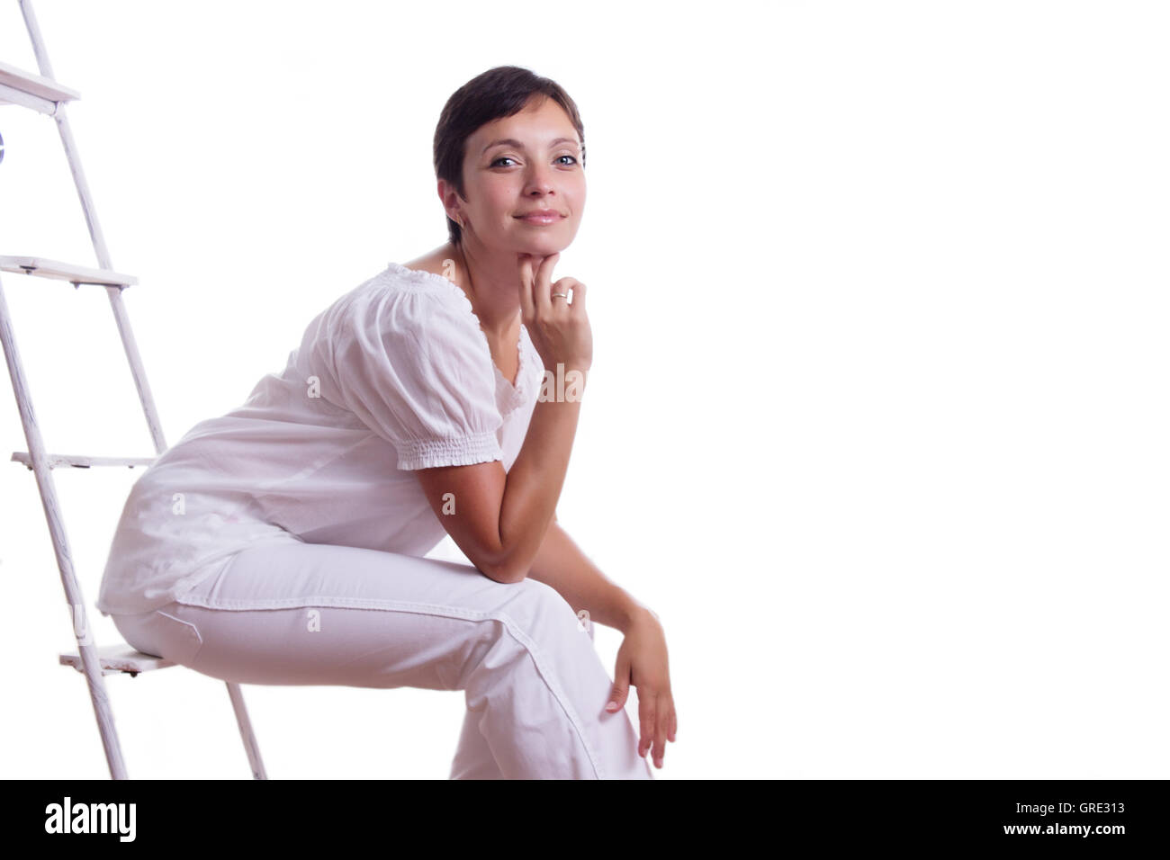 Happy woman sitting on step ladder Stock Photo - Alamy