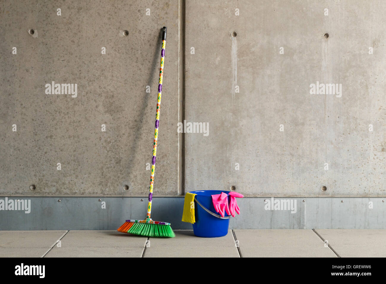 Colorful cleaning equipment (broom, bucket, rag and gloves) in front of ...