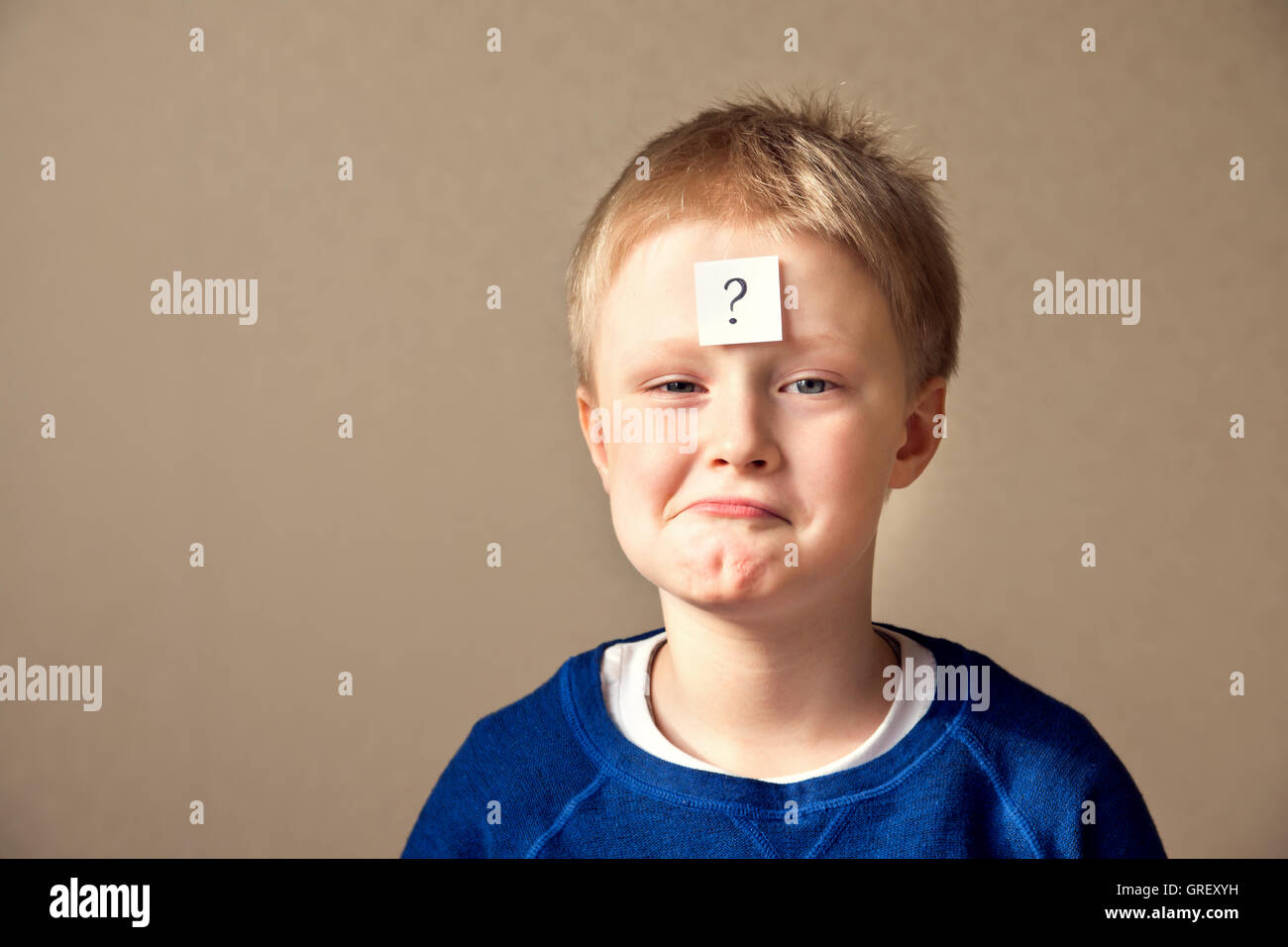 thinking young boy with question mark has secret on gray background ...