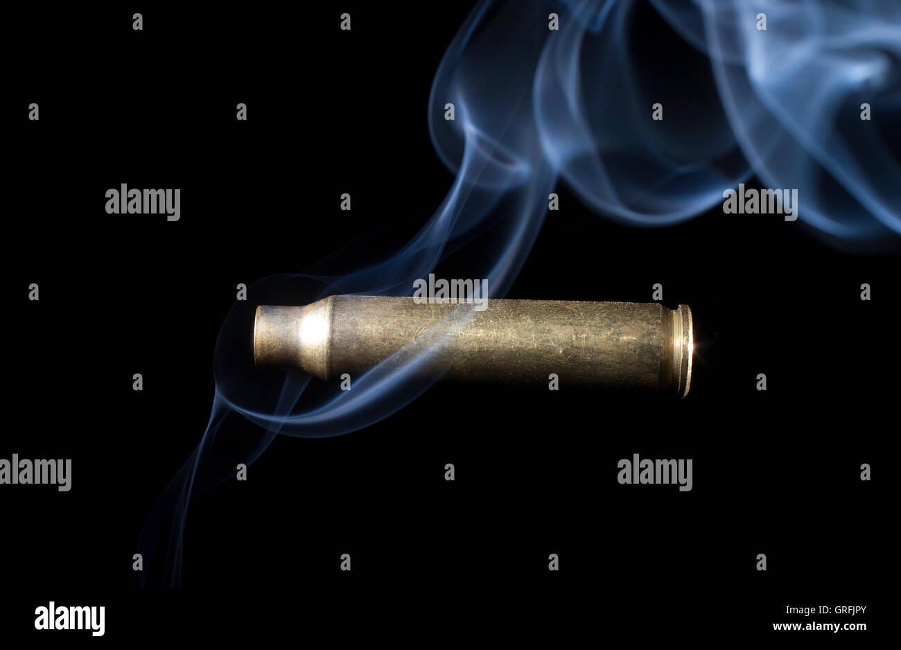 Empty casing from a rifle that has smoke around on a black background ...