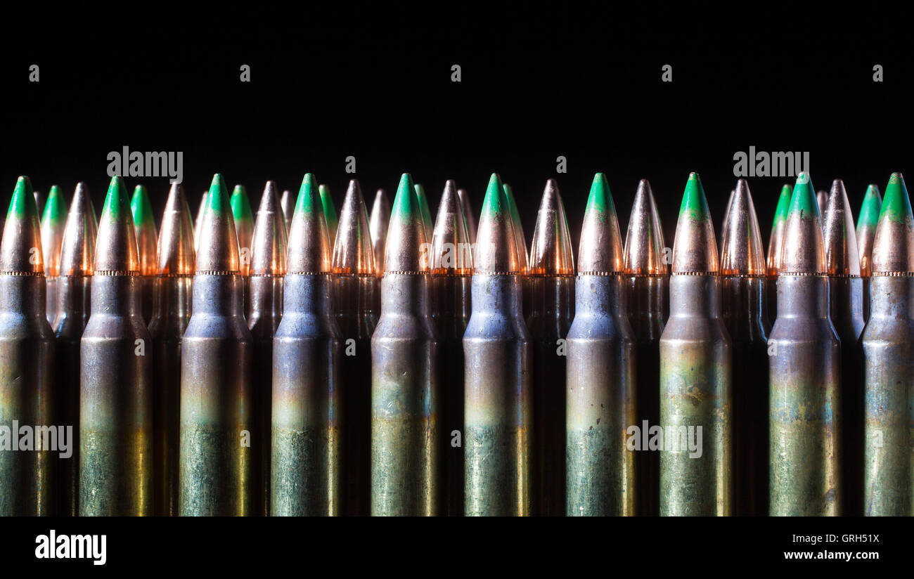 Long line of rifle cartridges and some of the bullets have green tips ...