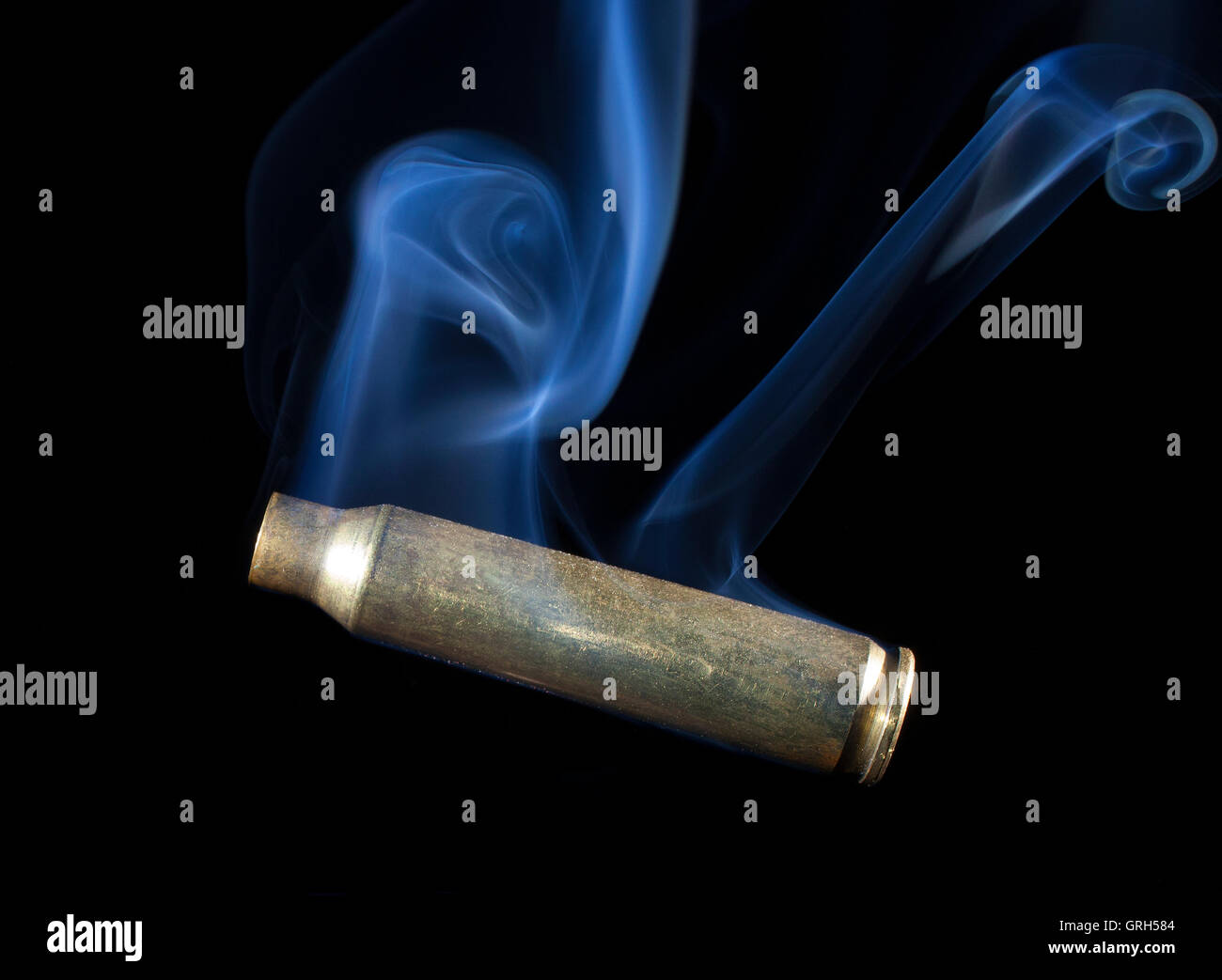 Brass case from a cartridge that has smoke on a black background Stock ...
