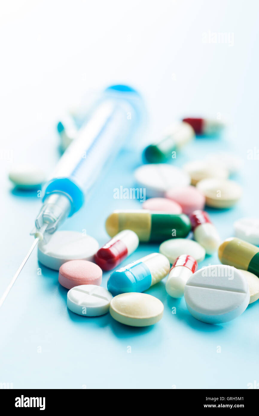 The different pills and syringe on blue background Stock Photo - Alamy