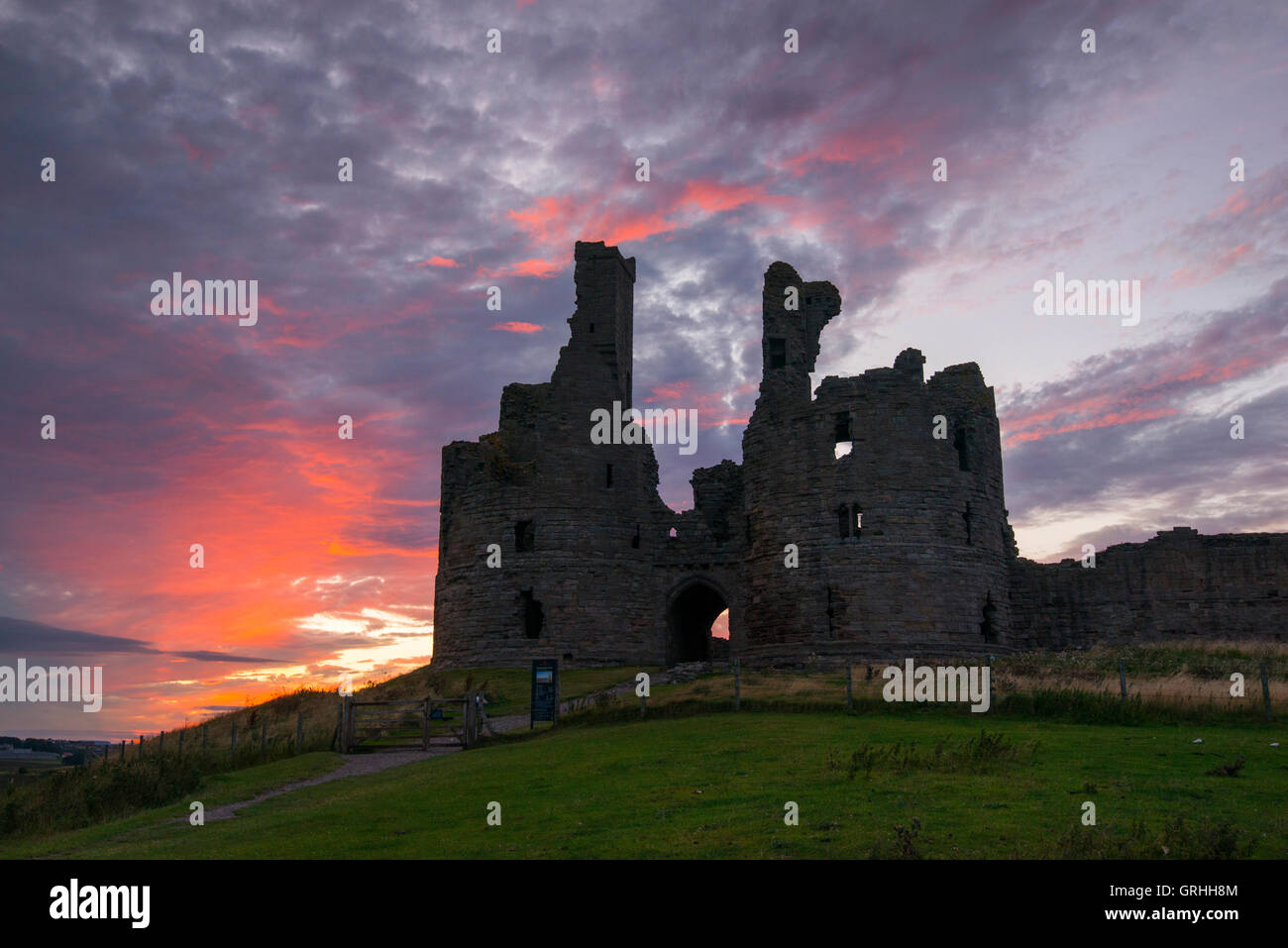 The foreboding ruins of Dunstanburgh Castle at sunset on the coast of ...