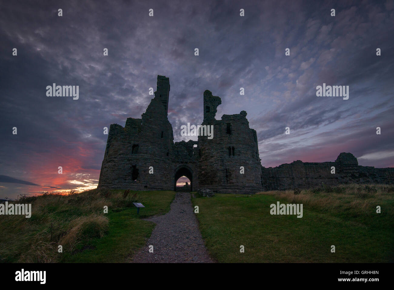 The foreboding ruins of Dunstanburgh Castle at sunset on the coast of ...