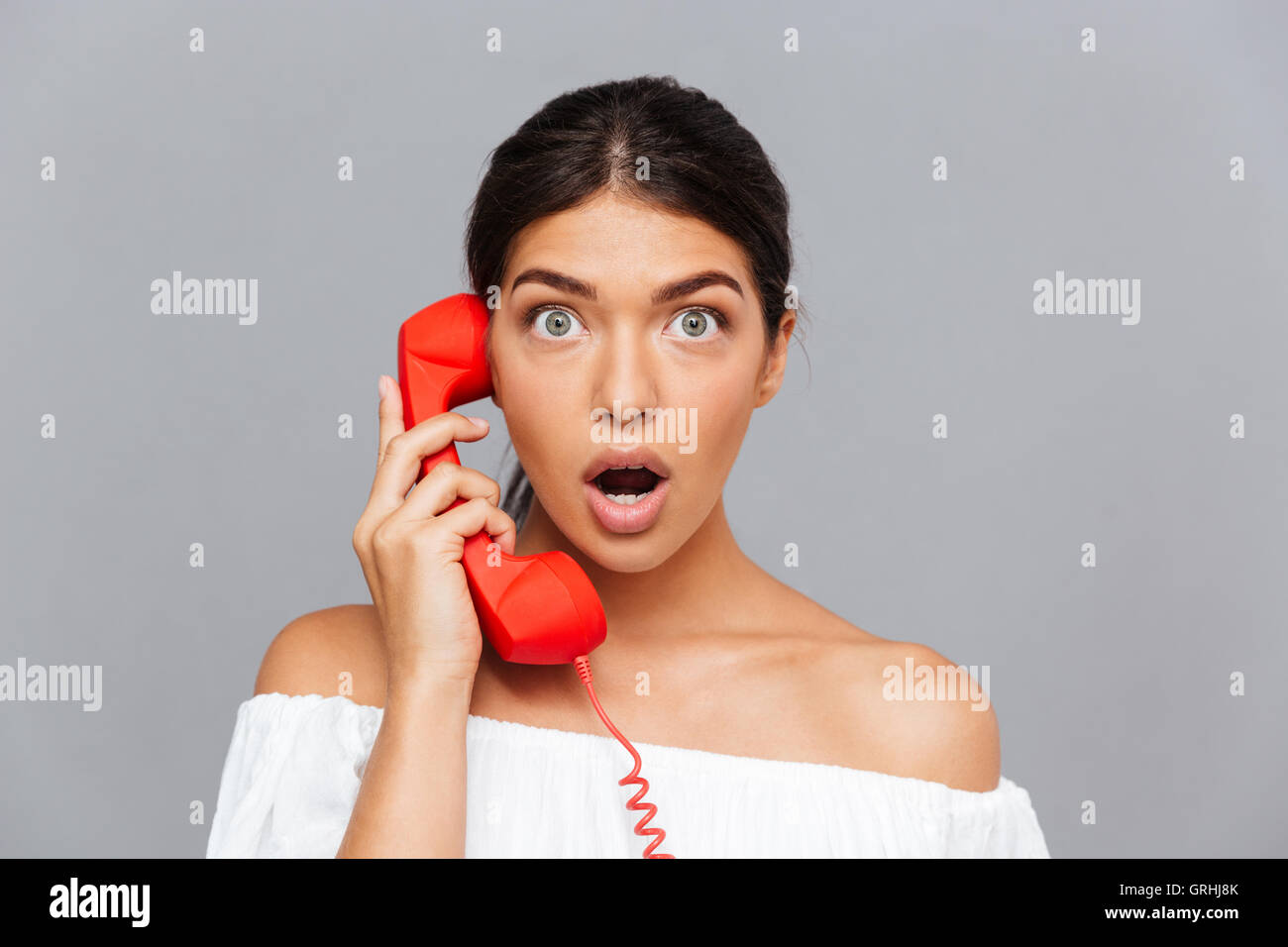Close up portrait of amazed beautiful woman talking on the phone tube ...