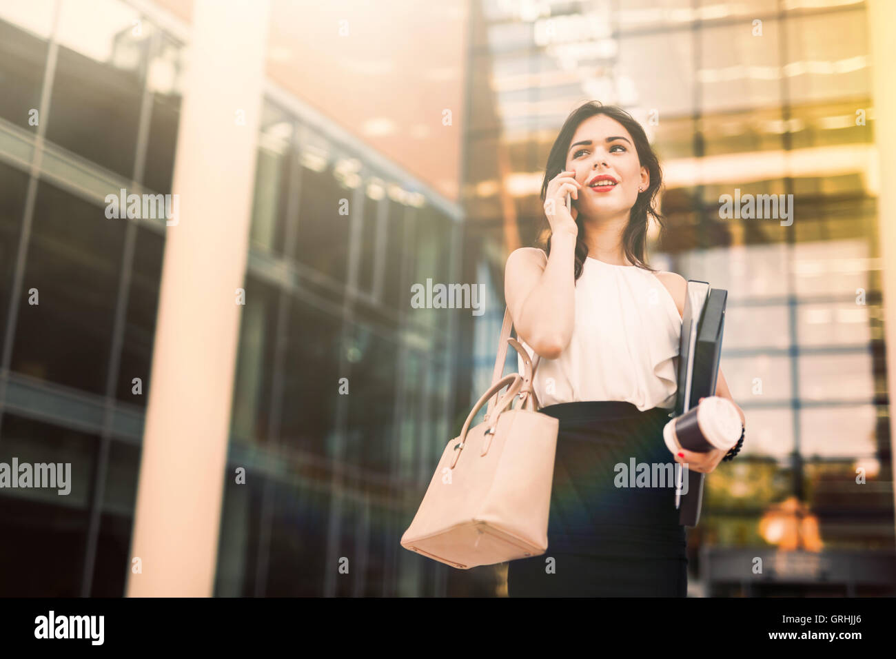 Busy businesswoman talking on phone outdoors Stock Photo - Alamy