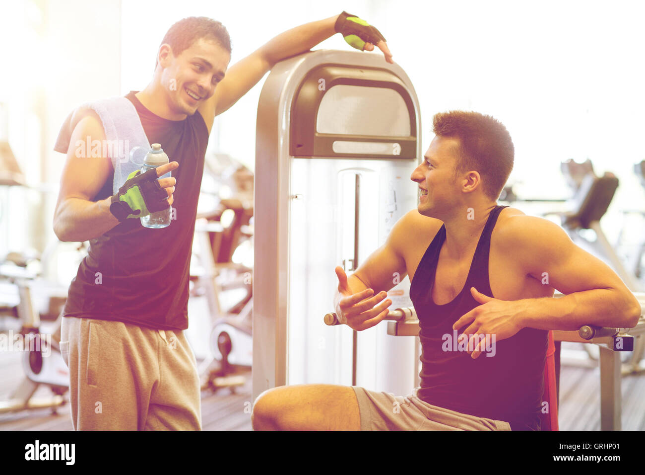 smiling men exercising on gym machine Stock Photo - Alamy