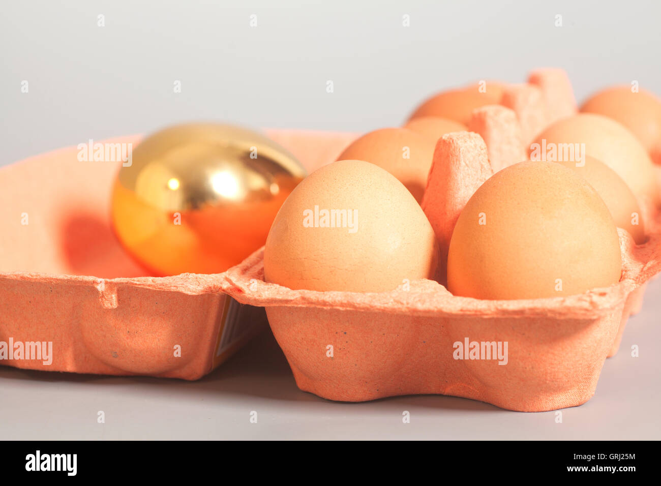 Cardboard egg box with golden and chicken eggs on gray background Stock ...
