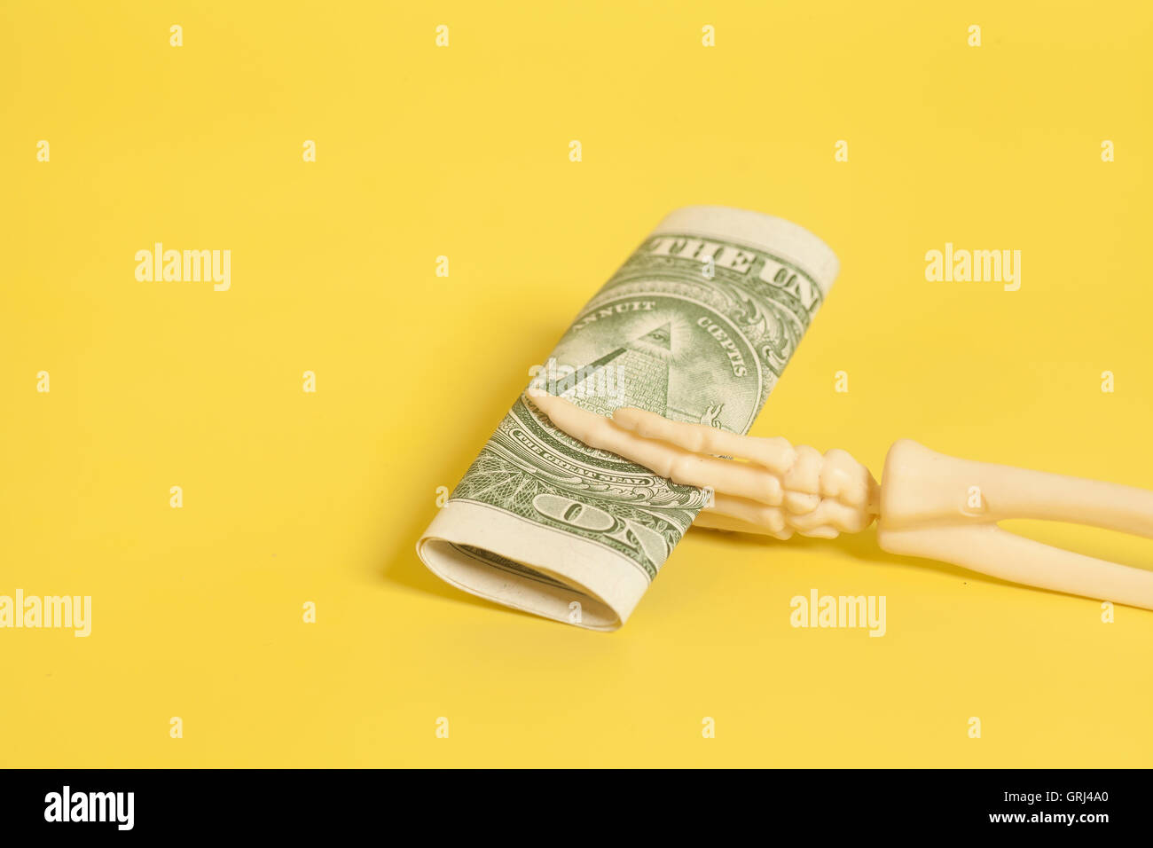 One dollar in skeleton hand on yellow background Stock Photo - Alamy
