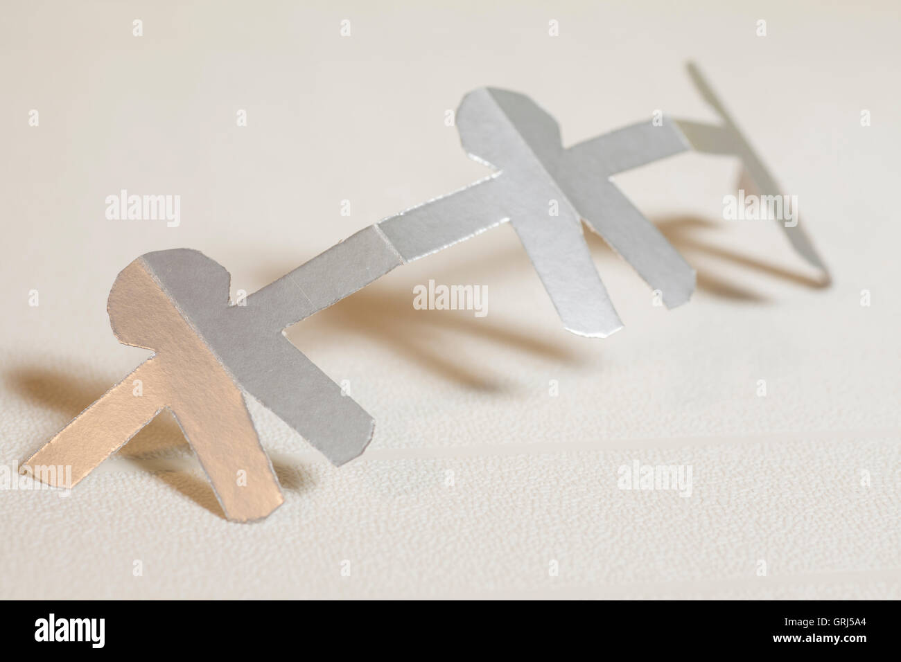 Folded Silver Paper People on gray background Stock Photo - Alamy