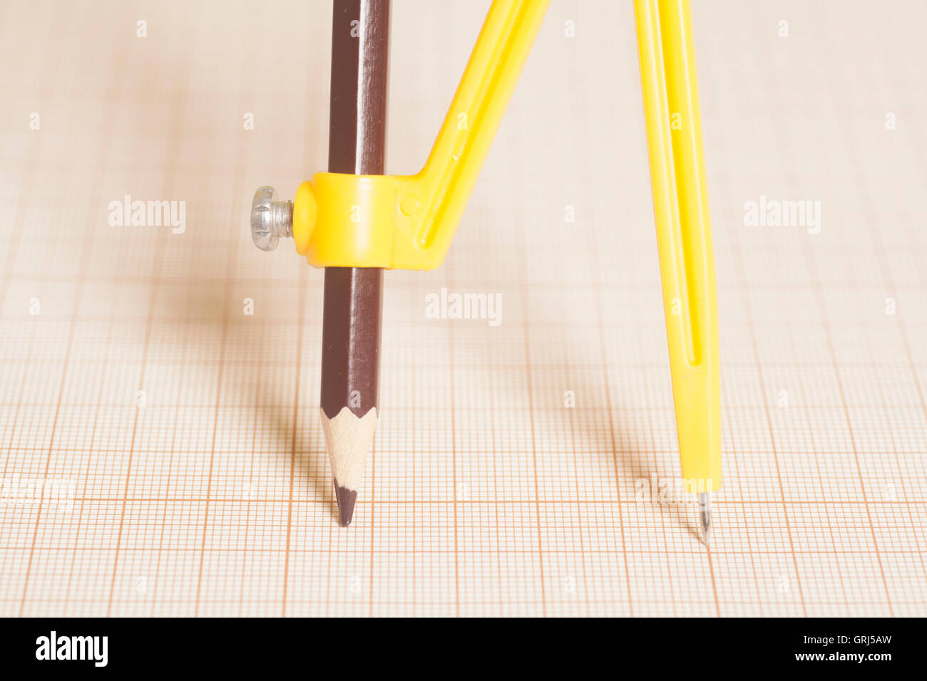 Yellow Drawing compass on graph paper Stock Photo - Alamy