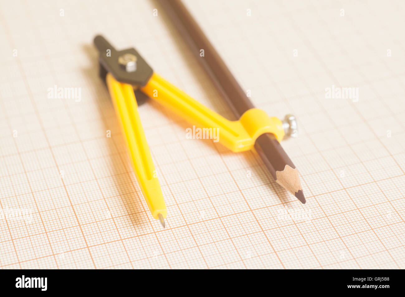 Yellow Drawing compass on graph paper Stock Photo - Alamy