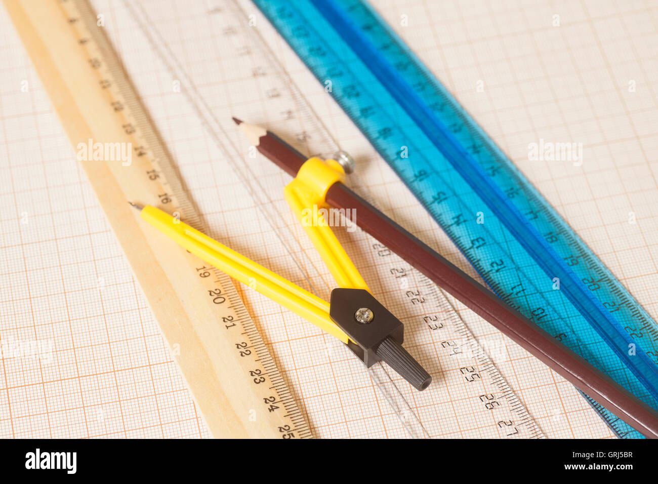 Yellow Drawing compass with black pencil and rulers on graph paper ...