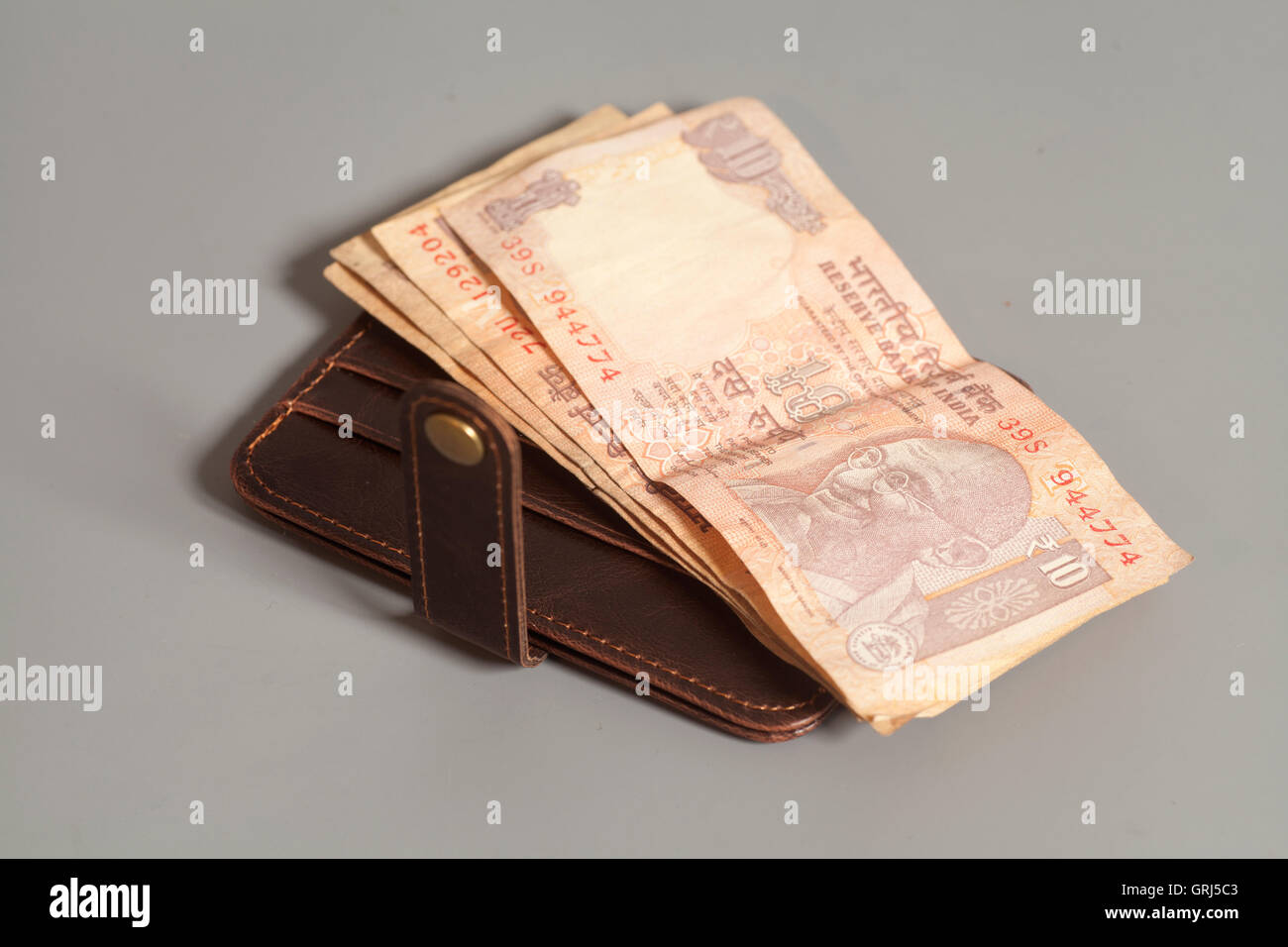 Brown leather wallet with Indian rupee currency on gray background ...