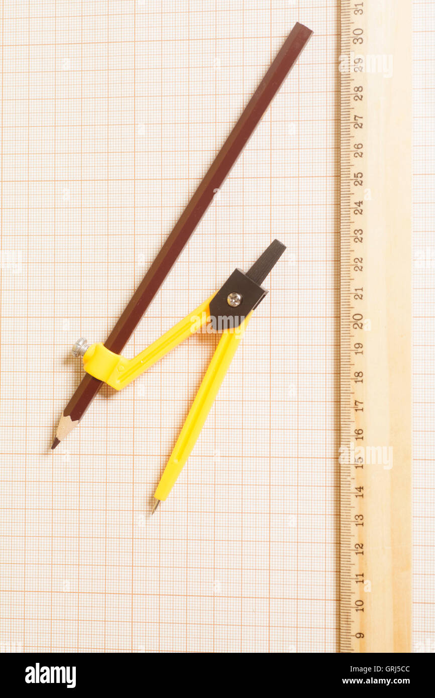 Yellow Drawing compass with black pencil and ruler on graph paper ...