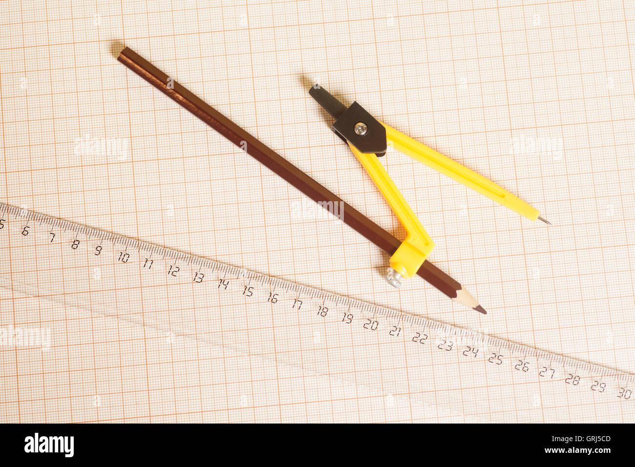 Yellow Drawing compass with black pencil and ruler on graph paper ...