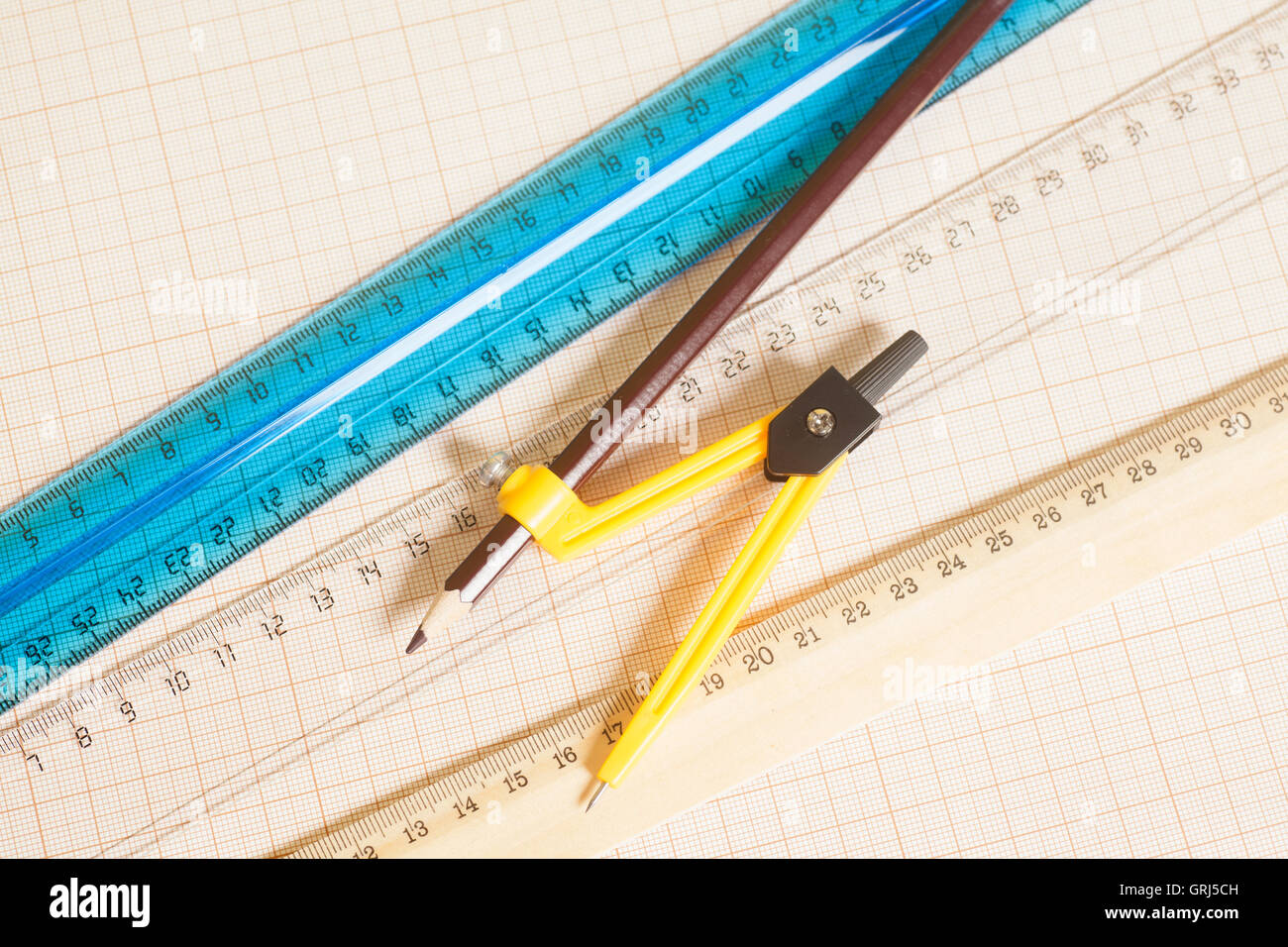 Yellow Drawing compass with black pencil and rulers on graph paper ...