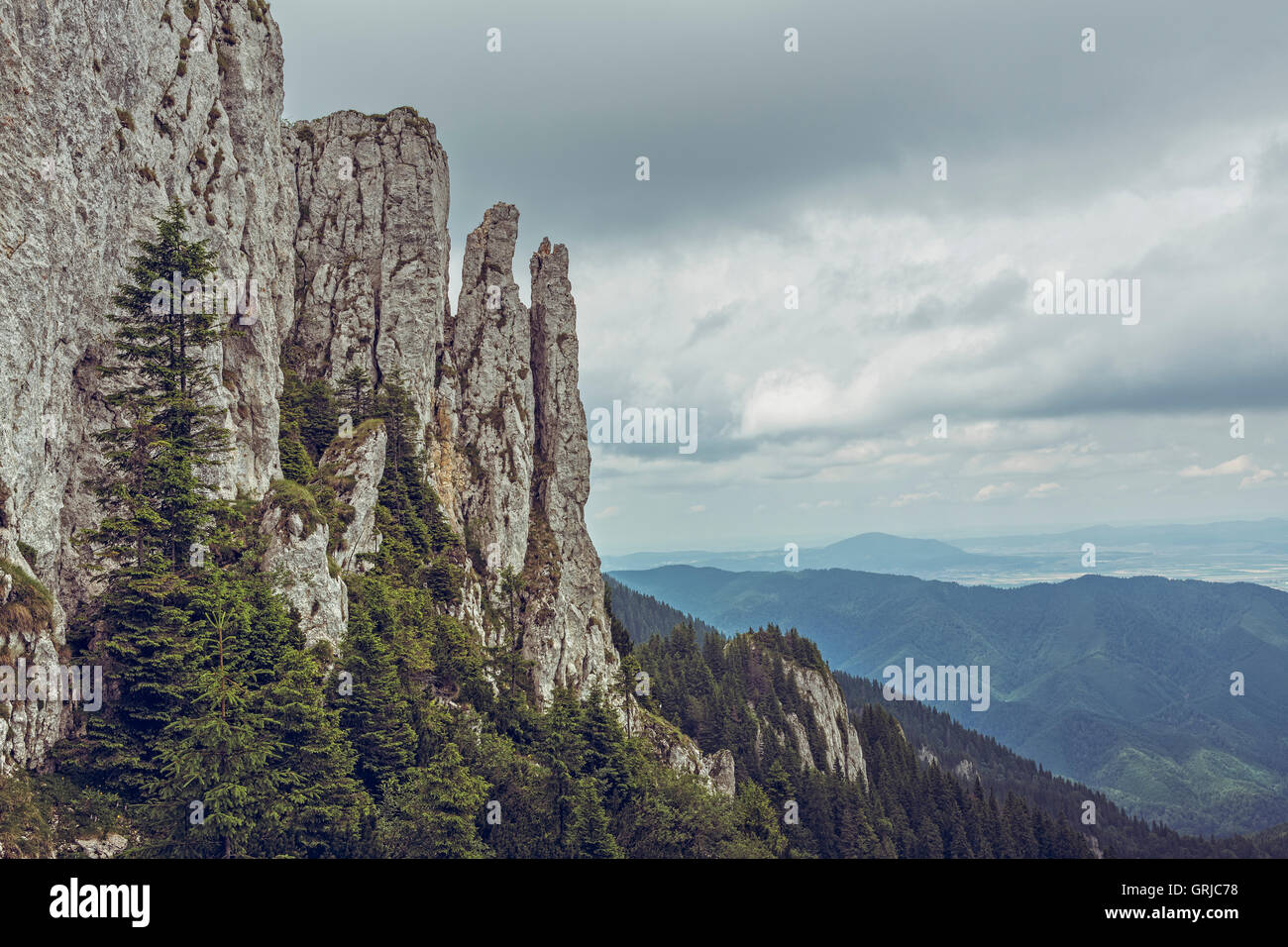 Alpine scenery with steep vertical rock cliff on a cloudy day in Piatra ...
