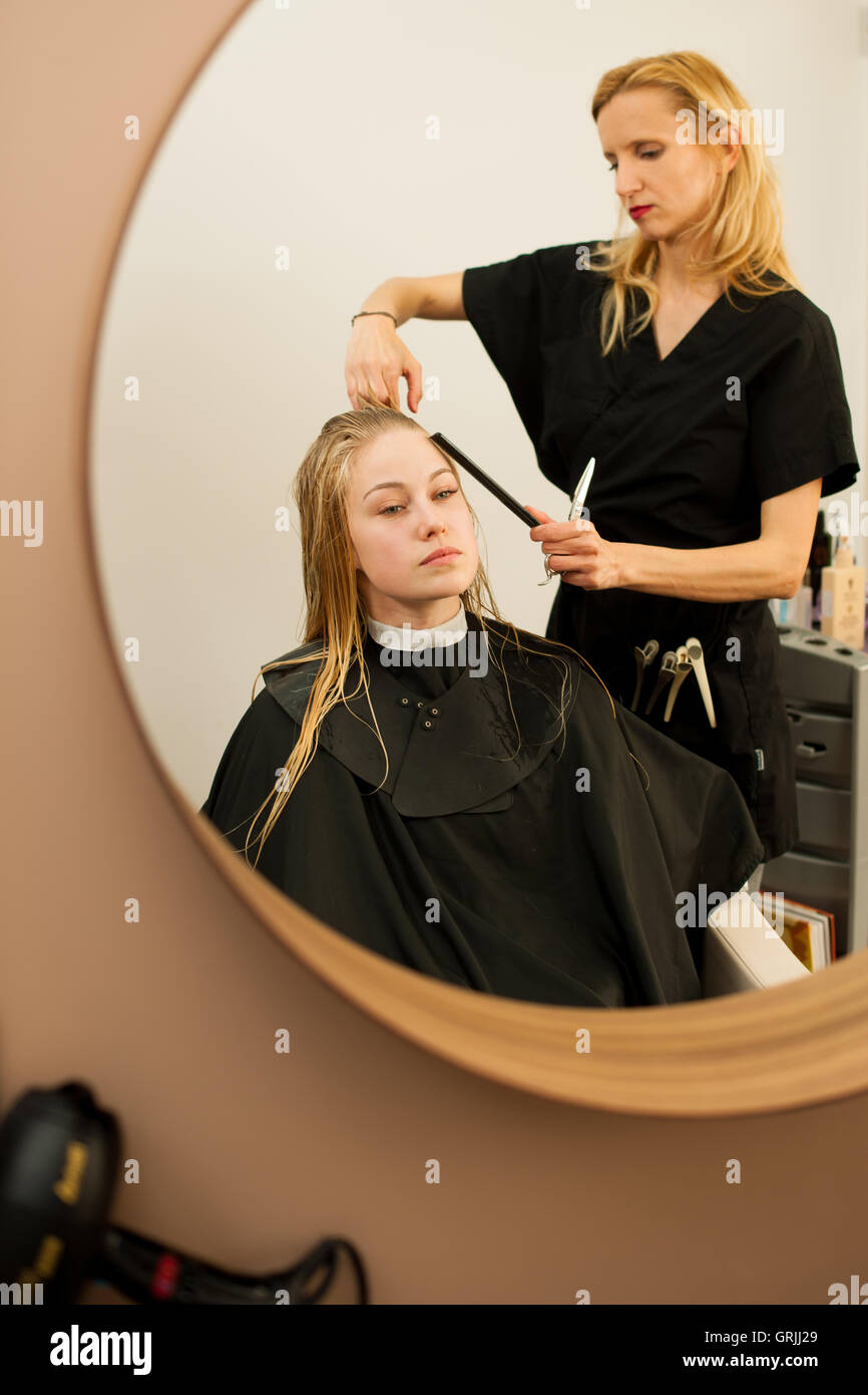 Hair stylist at work - hairdresser cutting hair to the customer before ...