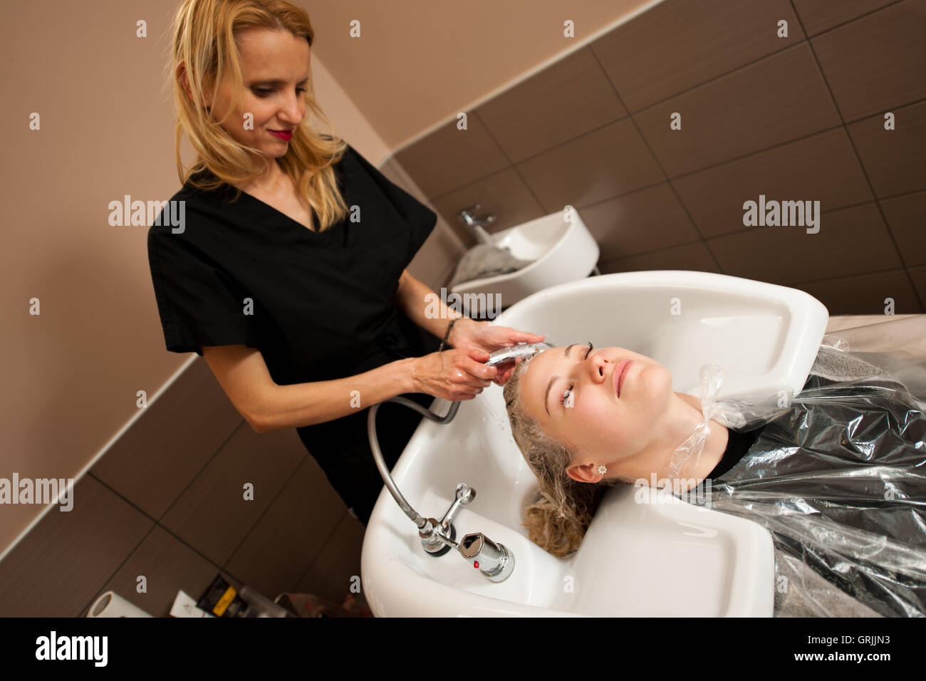 Hair stylist at work - hairdresser washing hair to the customer before ...