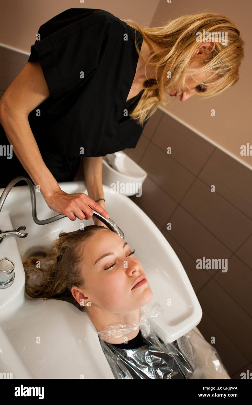 Hair stylist at work - hairdresser washing hair to the customer before ...