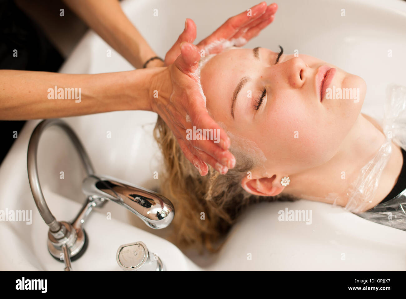 Hair stylist at work - hairdresser washing hair to the customer before ...