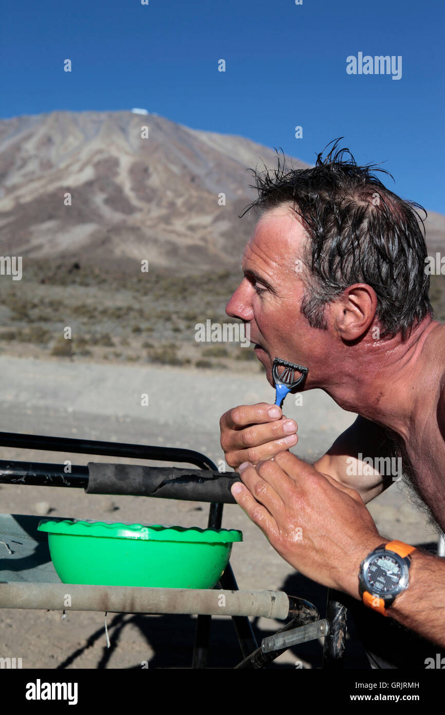 A man (expedition leader) shaves with primitive sources on the slopes ...