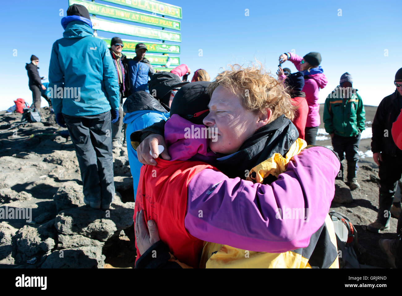 Two female hikers are crying of happiness and hugging on the summit of ...
