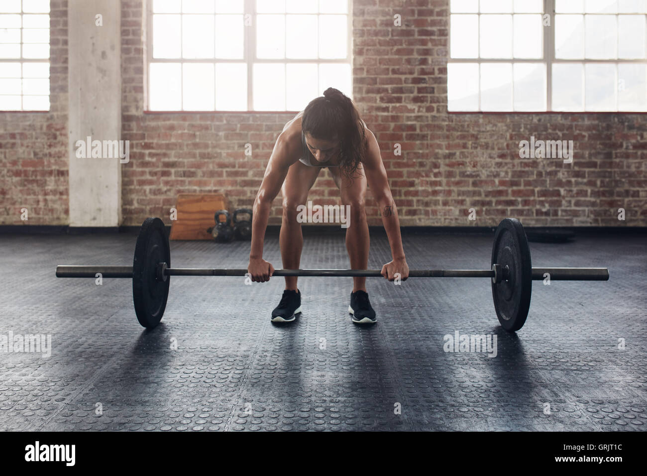 Full length of an fit young woman working out with a barbell at the gym ...