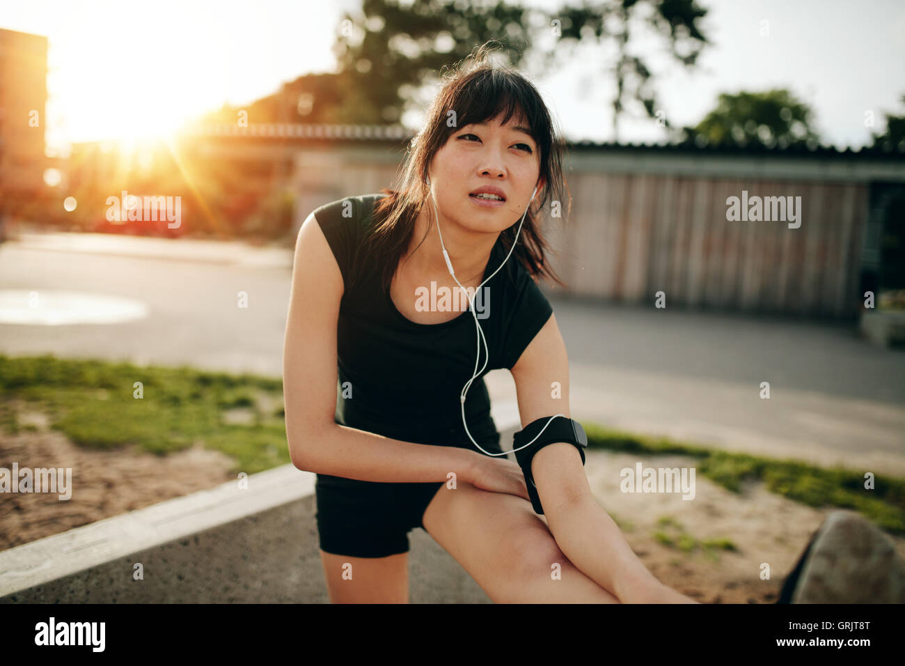 Active young female runner stretching her legs outdoor before running ...