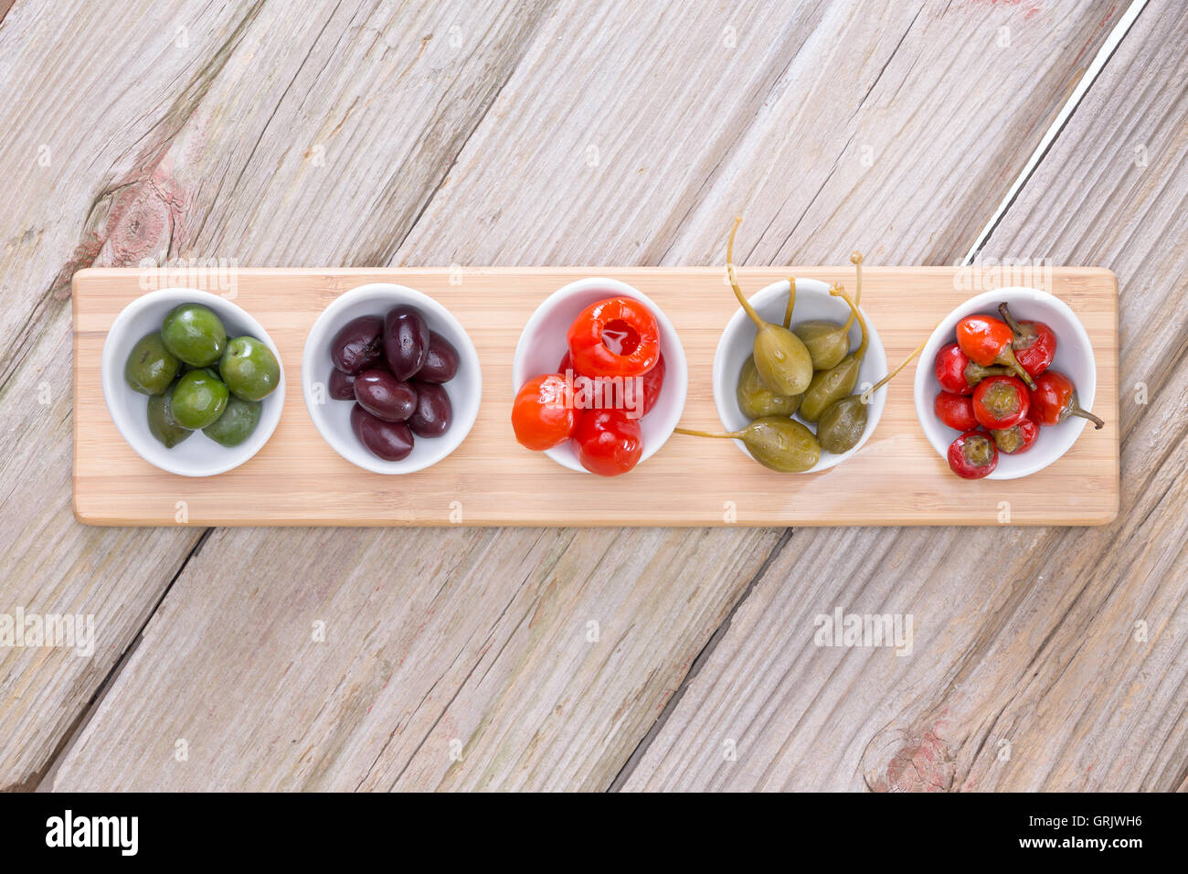 View from above of a line of assorted cured savory olives and peppers ...