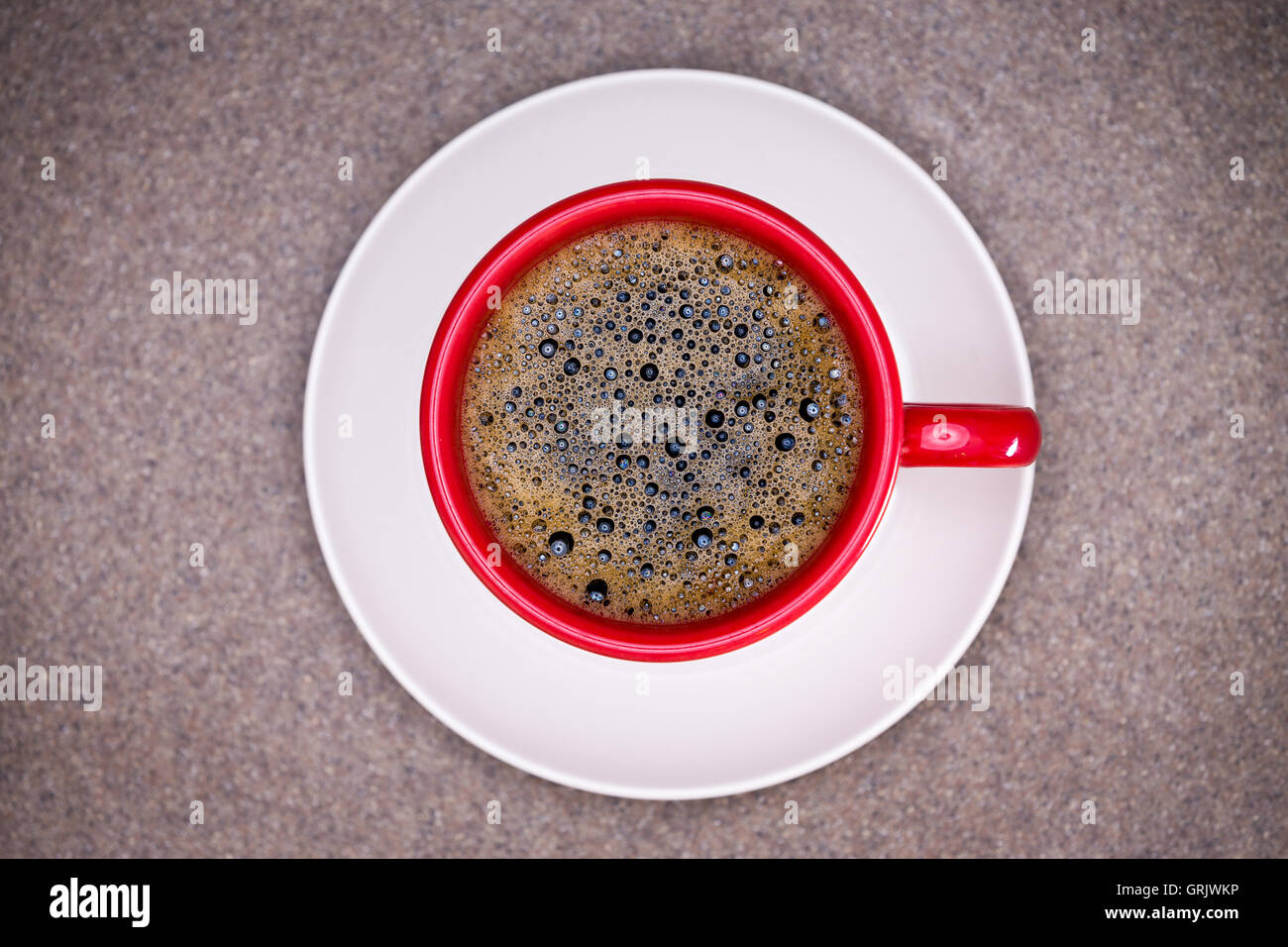 Freshly brewed frothy black espresso coffee in a red mug on a white ...