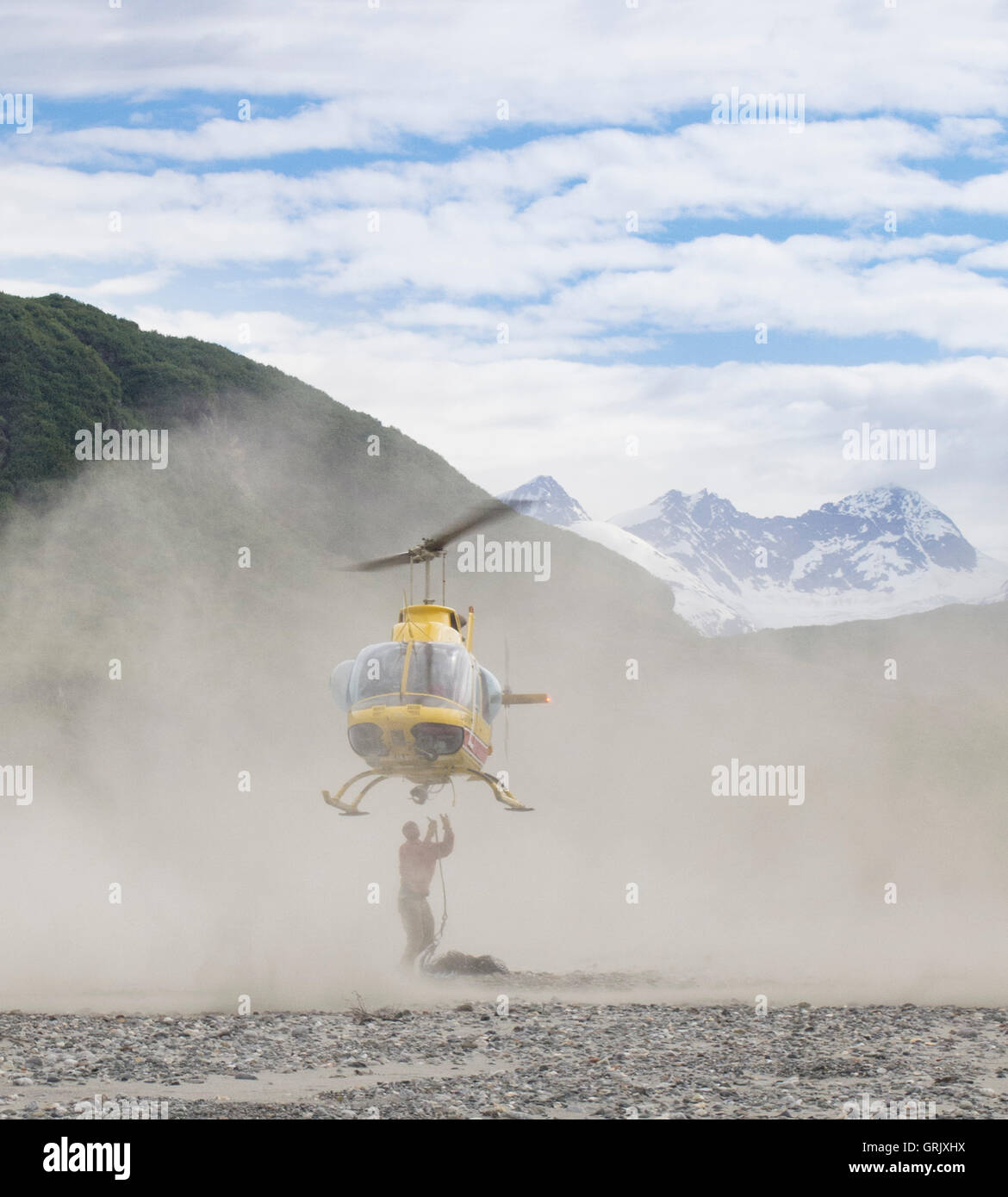 Rafter attaching load of rafting gear to the bottom of hovering ...