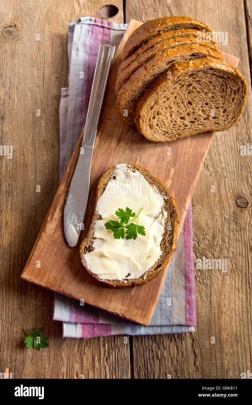 Butter and bread for breakfast, with parsley over rustic wooden ...
