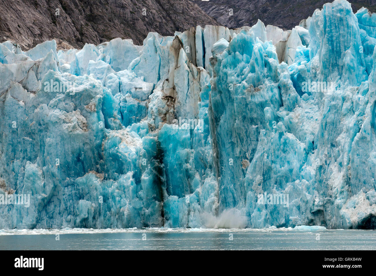 Dawes Glacier calves fall down into the Endicott Arm fjord of Tracy Arm ...