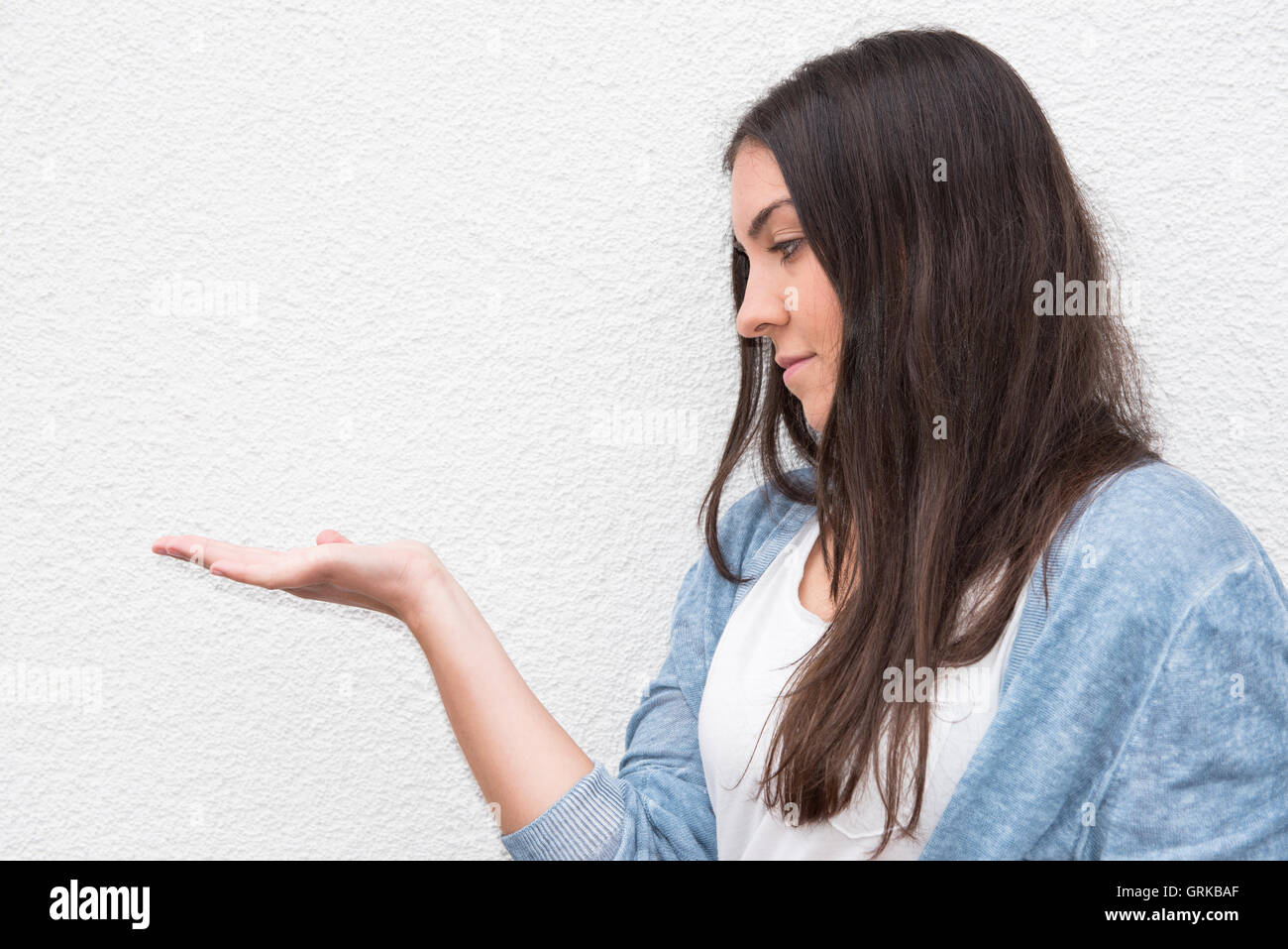 beautiful young woman holding up her hand before white wall Stock Photo ...