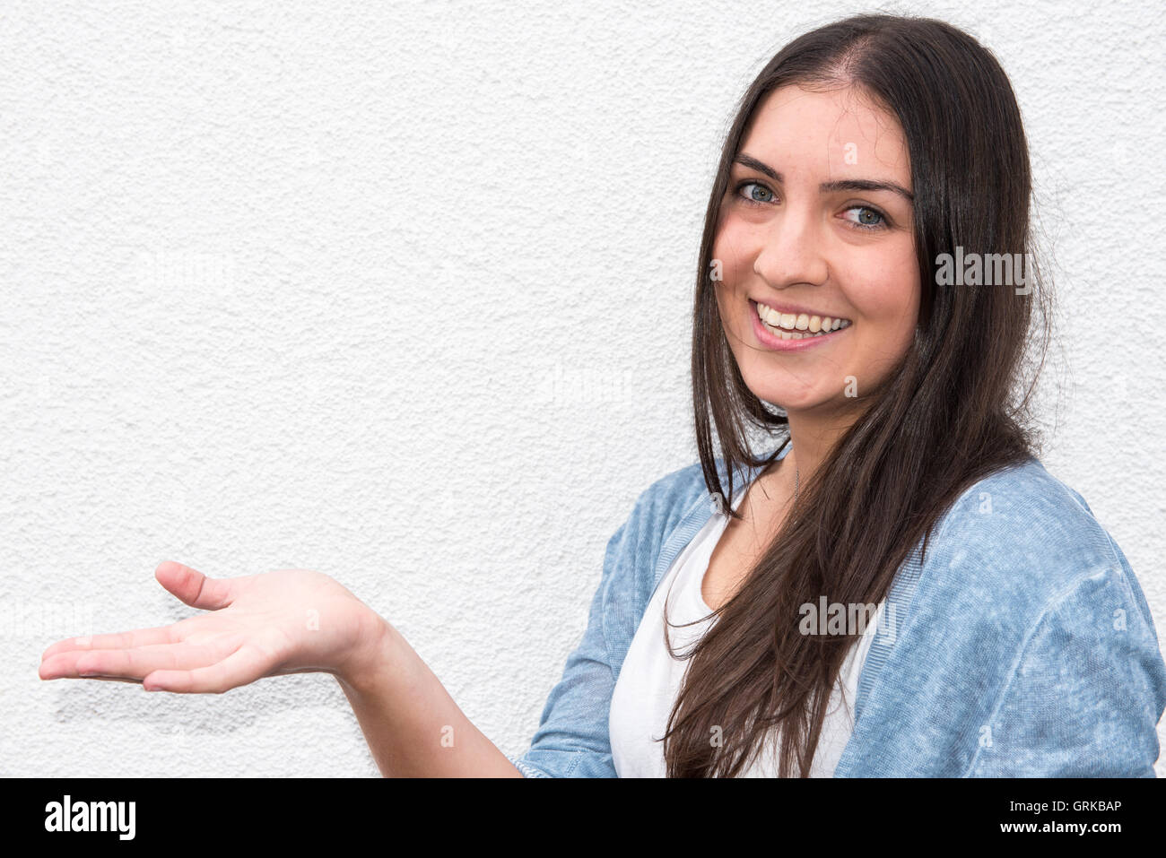 beautiful young woman holding up her hand before white wall Stock Photo ...