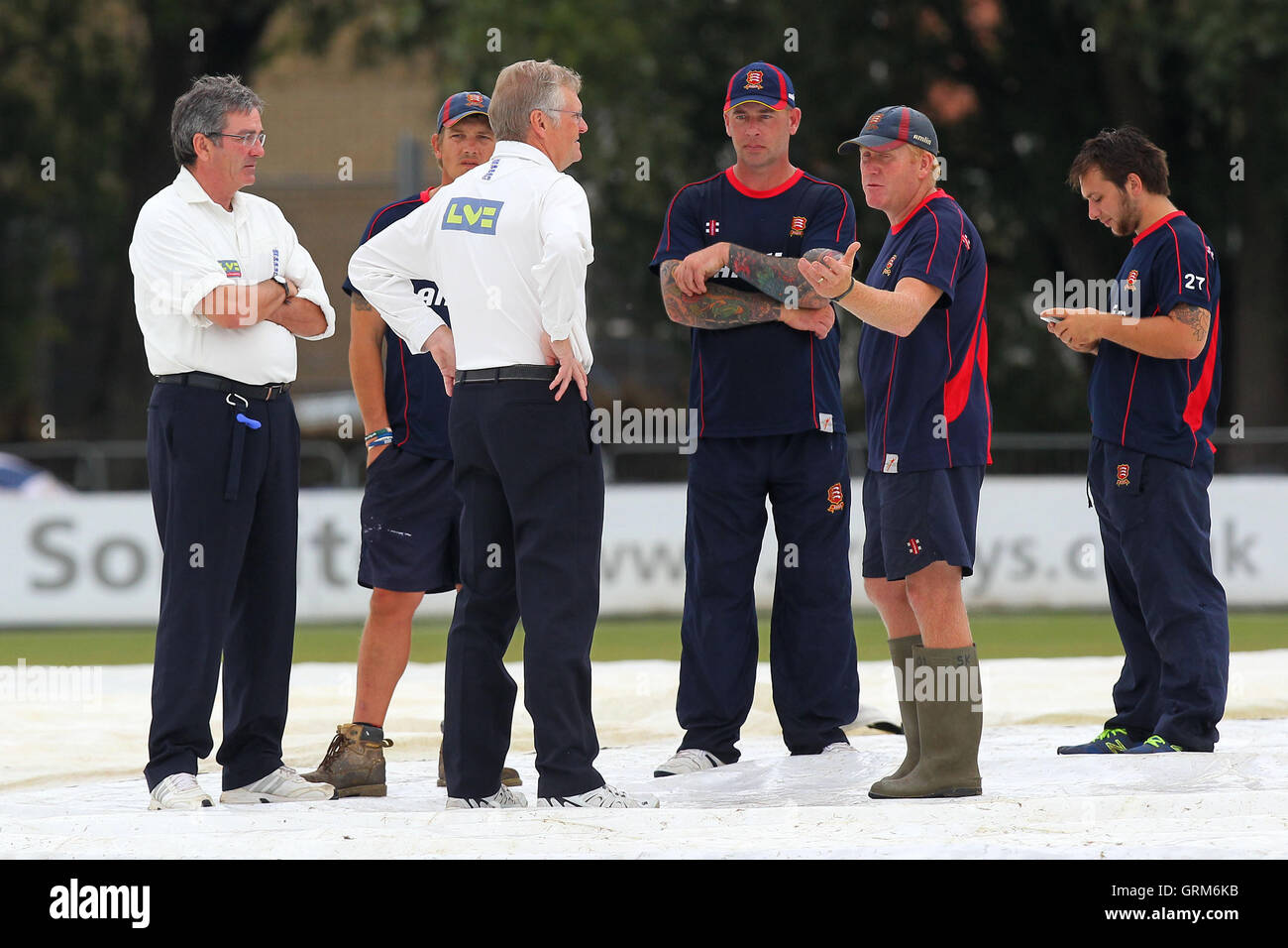 Umpires Nick Cook (L) and Steven Garratt meet with groundsman Stuart ...