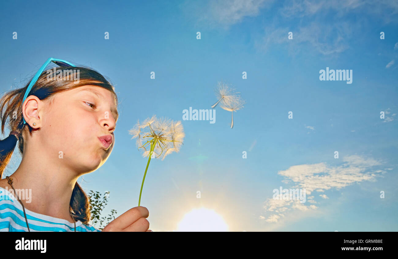 Young girl blowing dandelion Stock Photo - Alamy