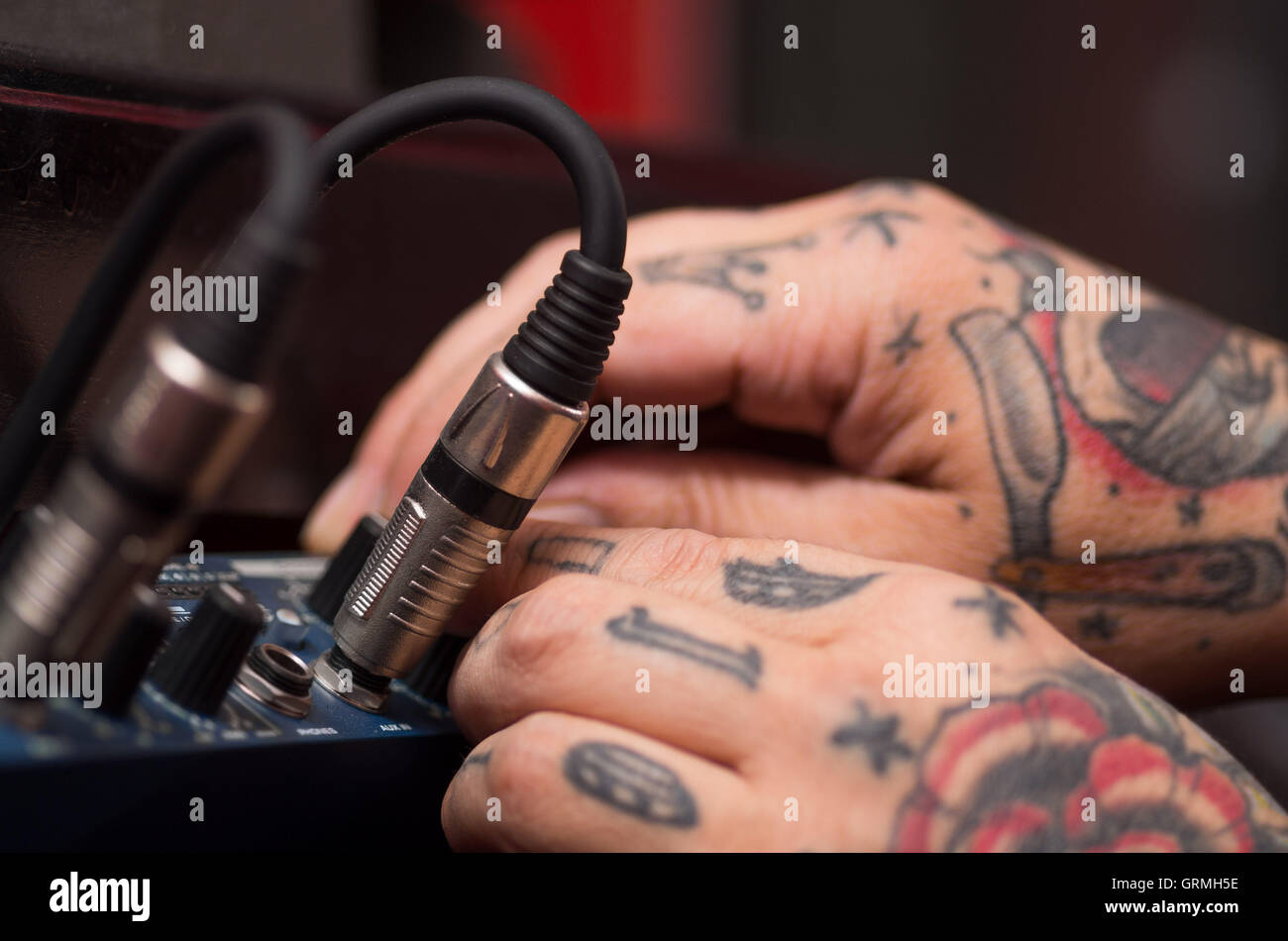 Closeup of hands covered with tattoos working on cable connection ...