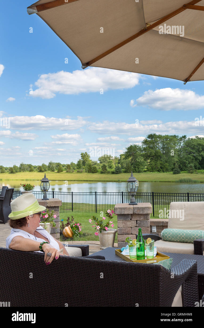 Rear view of a woman relaxing on an outdoor patio enjoying the view ...