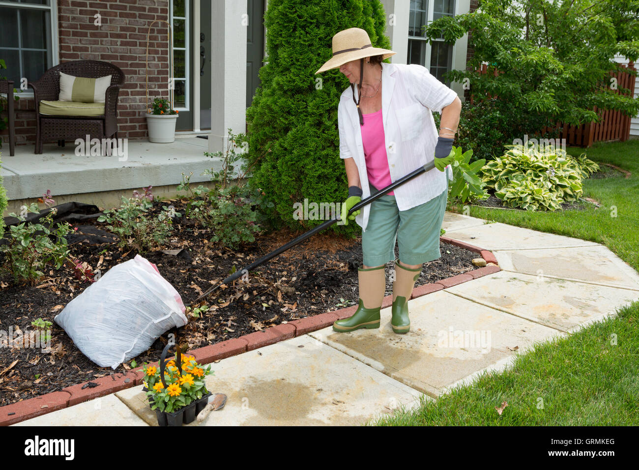 Older lady doing cleaning work in the yard preparing a flowerbed near ...