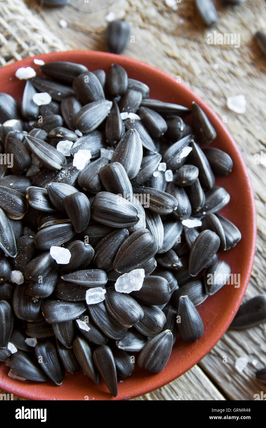 Sunflower seeds with sea salt in ceramic bowl over rustic wooden ...
