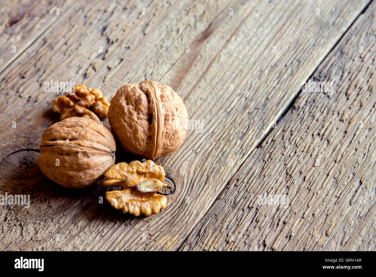 Walnut kernels and whole walnuts on rustic old wooden table with copy ...