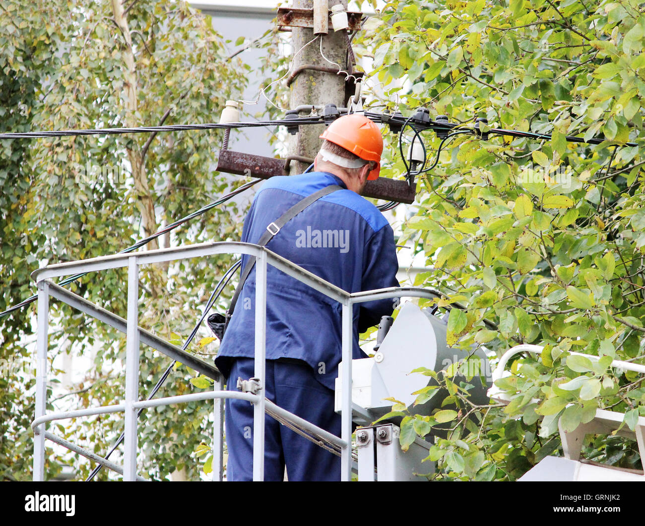 Electrical worker repairing the wires on the pole with the help of the ...